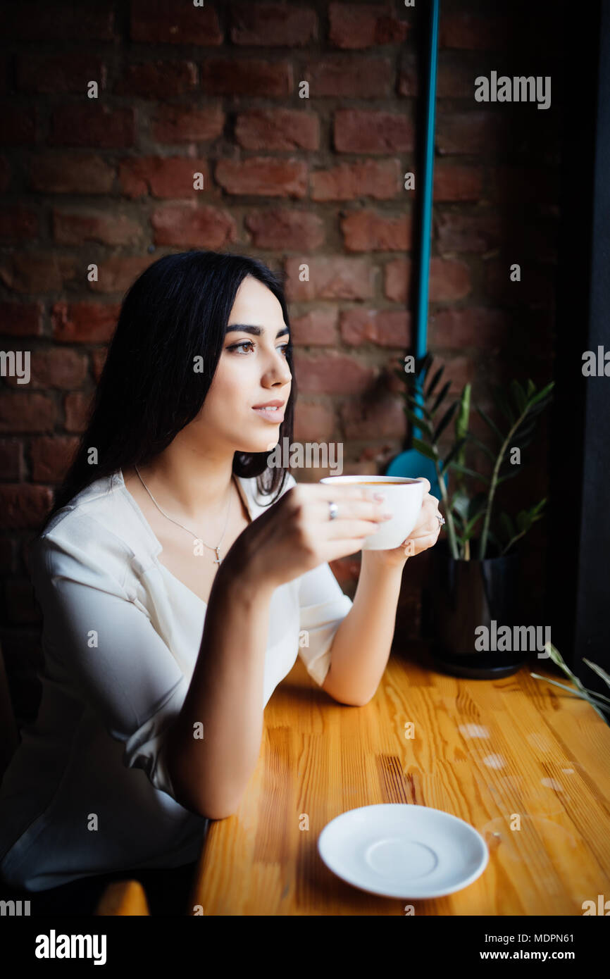 Young woman drinking coffee in a cafe outdoors Stock Photo - Alamy
