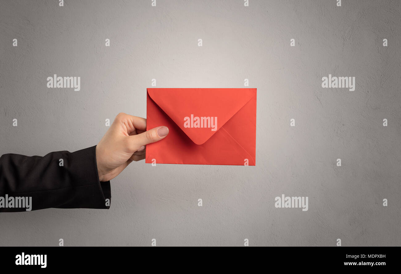 Female hand holding coloured and white envelope with empty wall ...