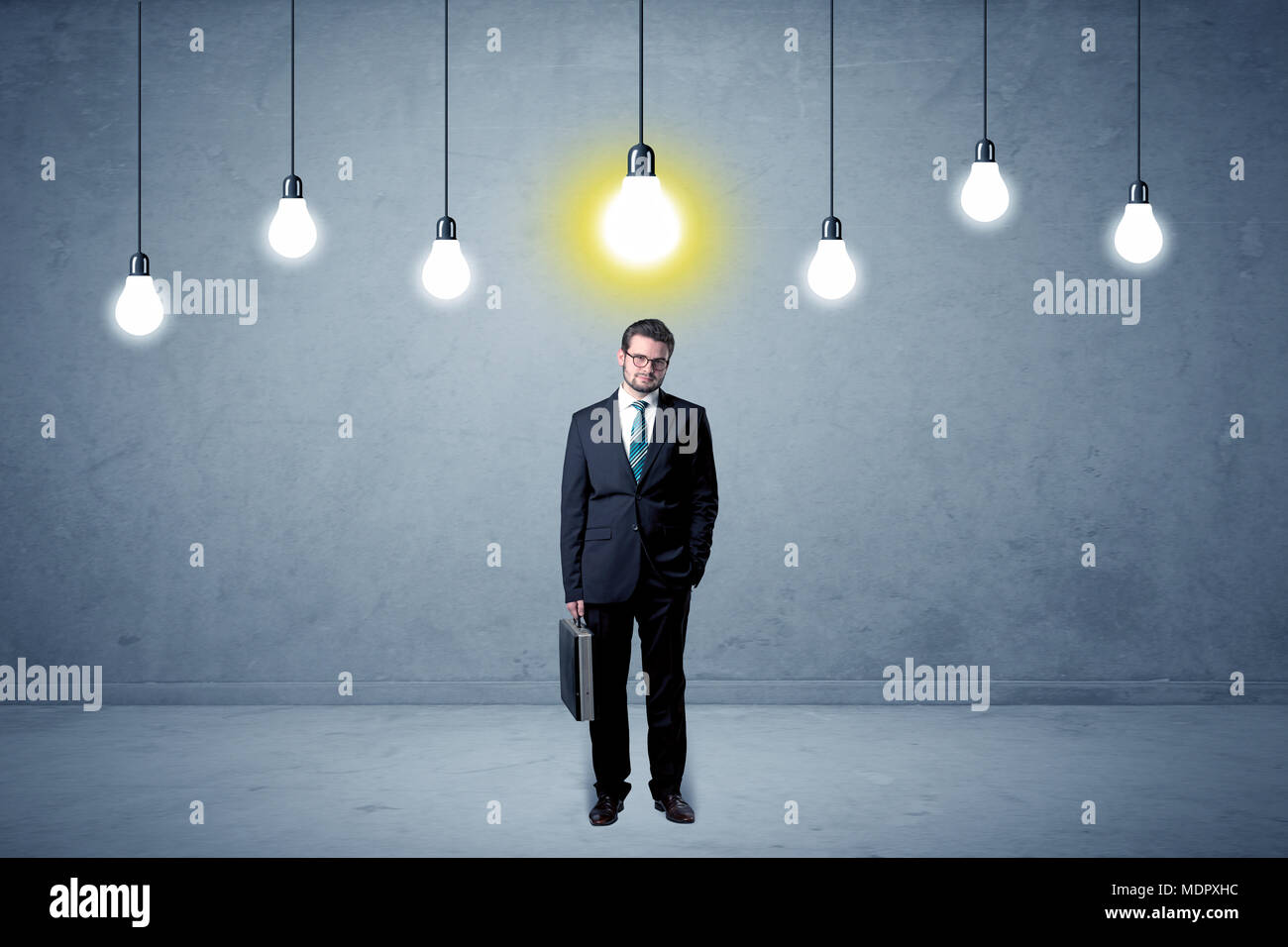Handsome businessman in an empty space with bulbs above and uninspired ...