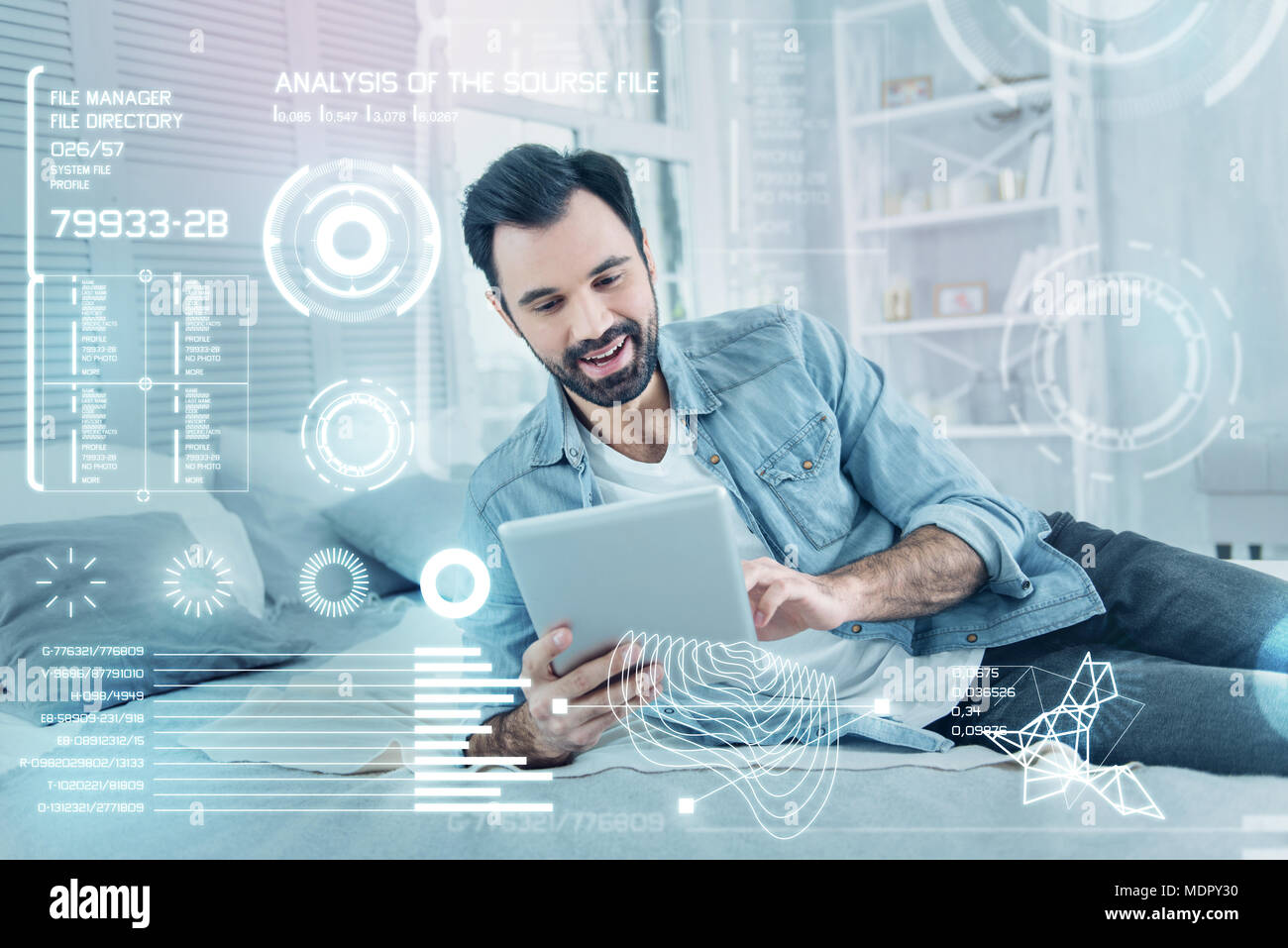 Positive actor relaxing on the bed and watching films on the tablet ...