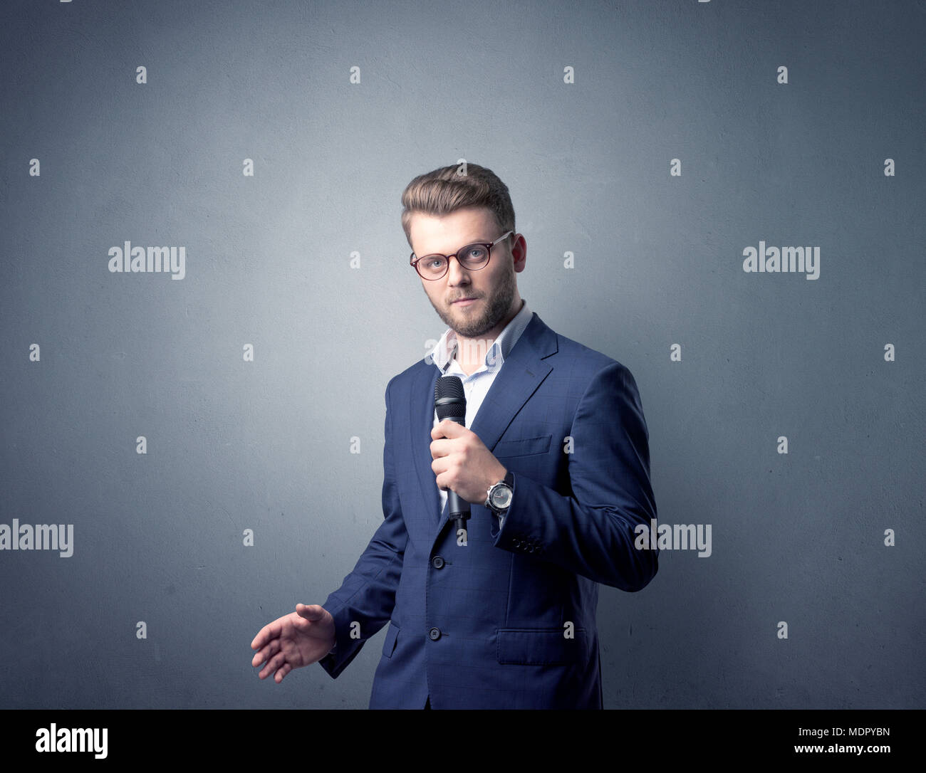 Businessman speaking into microphone with blue background Stock Photo ...