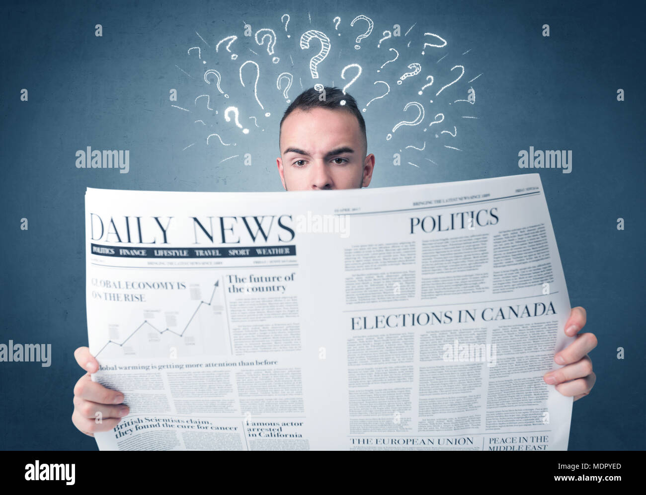 Young confused businessman reading daily newspaper with question marks ...