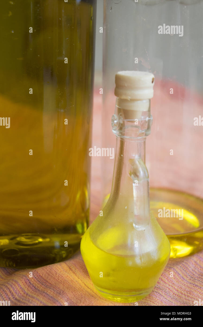 small glass oil cruet with olive oil and on the background olive oil ...