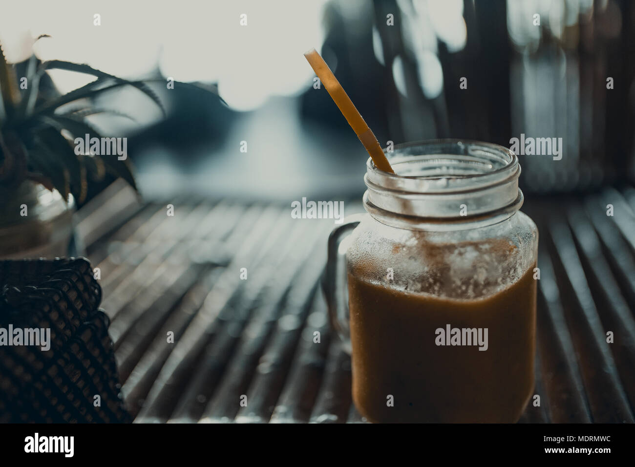Jar with ice fruit shake and straw inside standing on the bamboo table ...