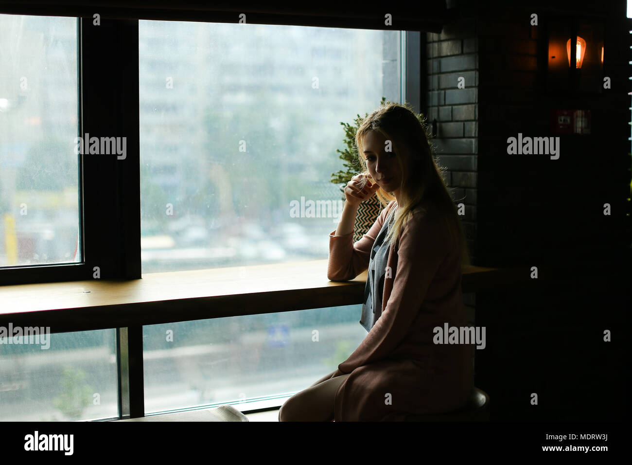 Blonde girl sitting near window at cafe Stock Photo - Alamy