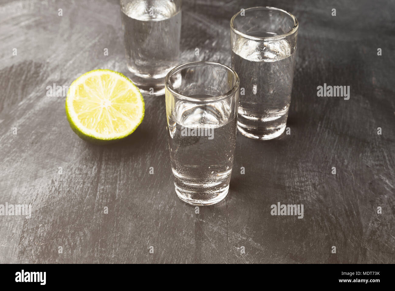 Cold vodka in shot glasses on a black background. Toned Stock Photo - Alamy