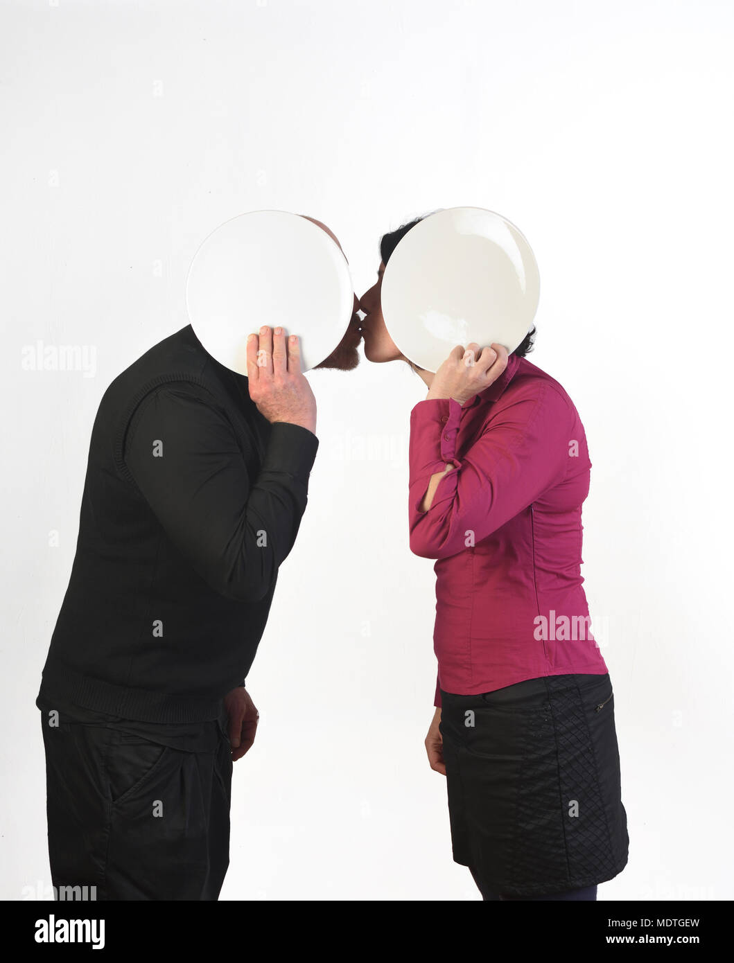 a loving couple kissing each other hidden behind a plate Stock Photo ...