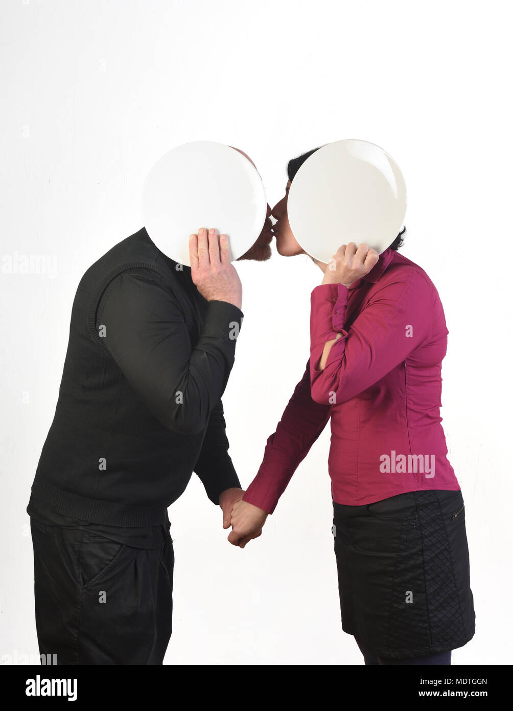 a loving couple kissing each other hidden behind a plate Stock Photo ...