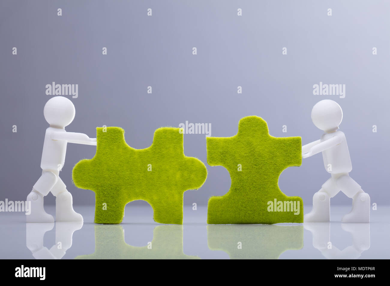 Side View Of Two Miniature Human Figures Solving Green Jigsaw Puzzles ...