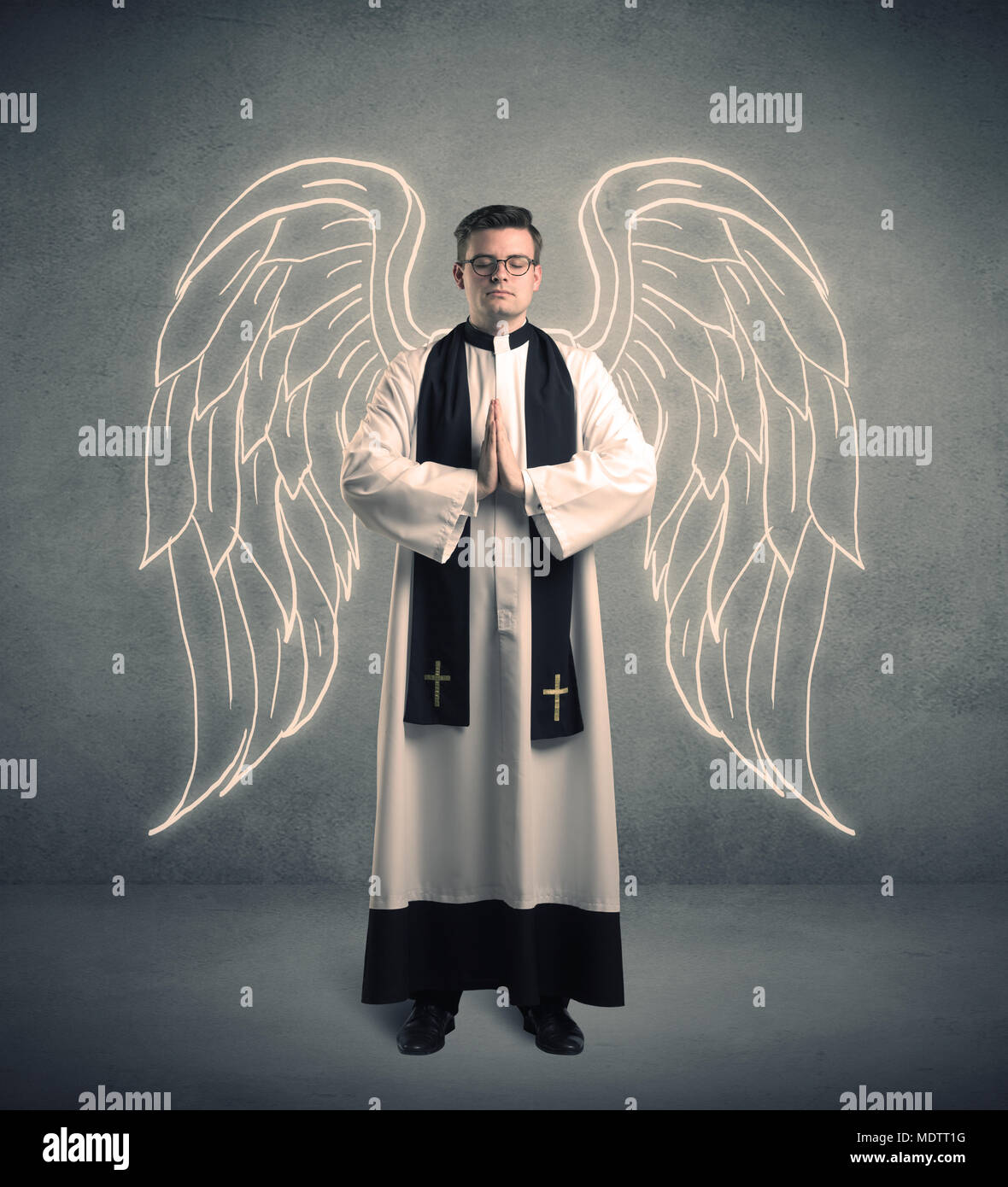 A young male priest with drawn large angel wings standing with the holy ...