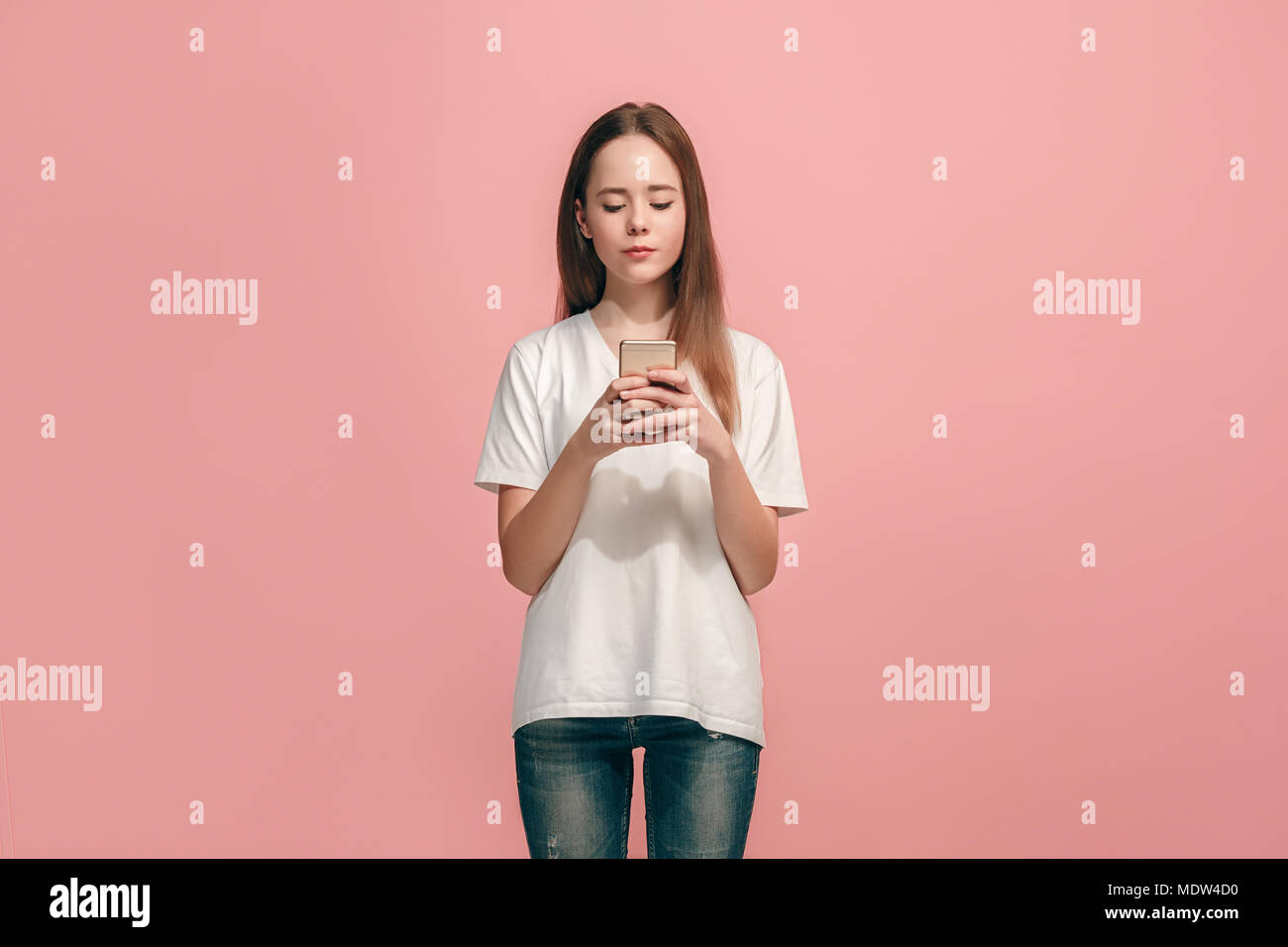 The happy teen girl standing and smiling against pink background Stock ...