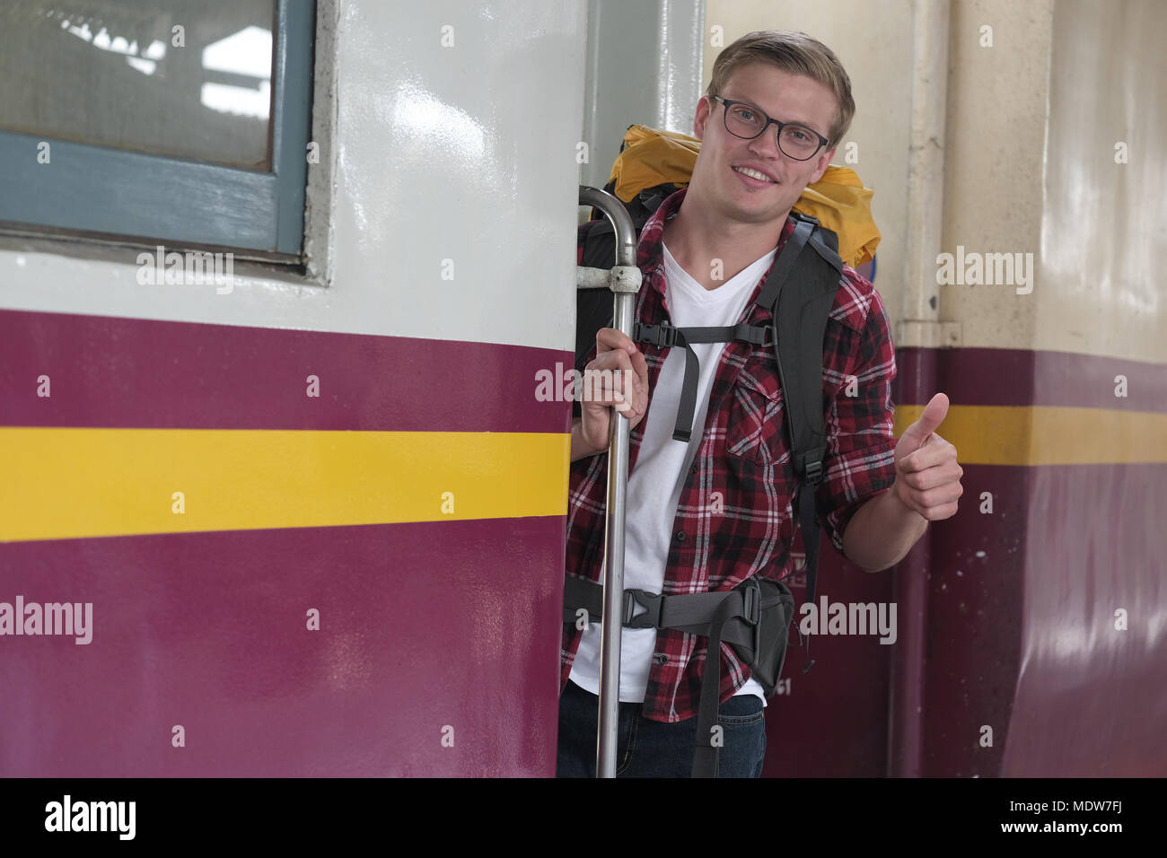 man traveler with backpack shows thumb up on train at railway station ...