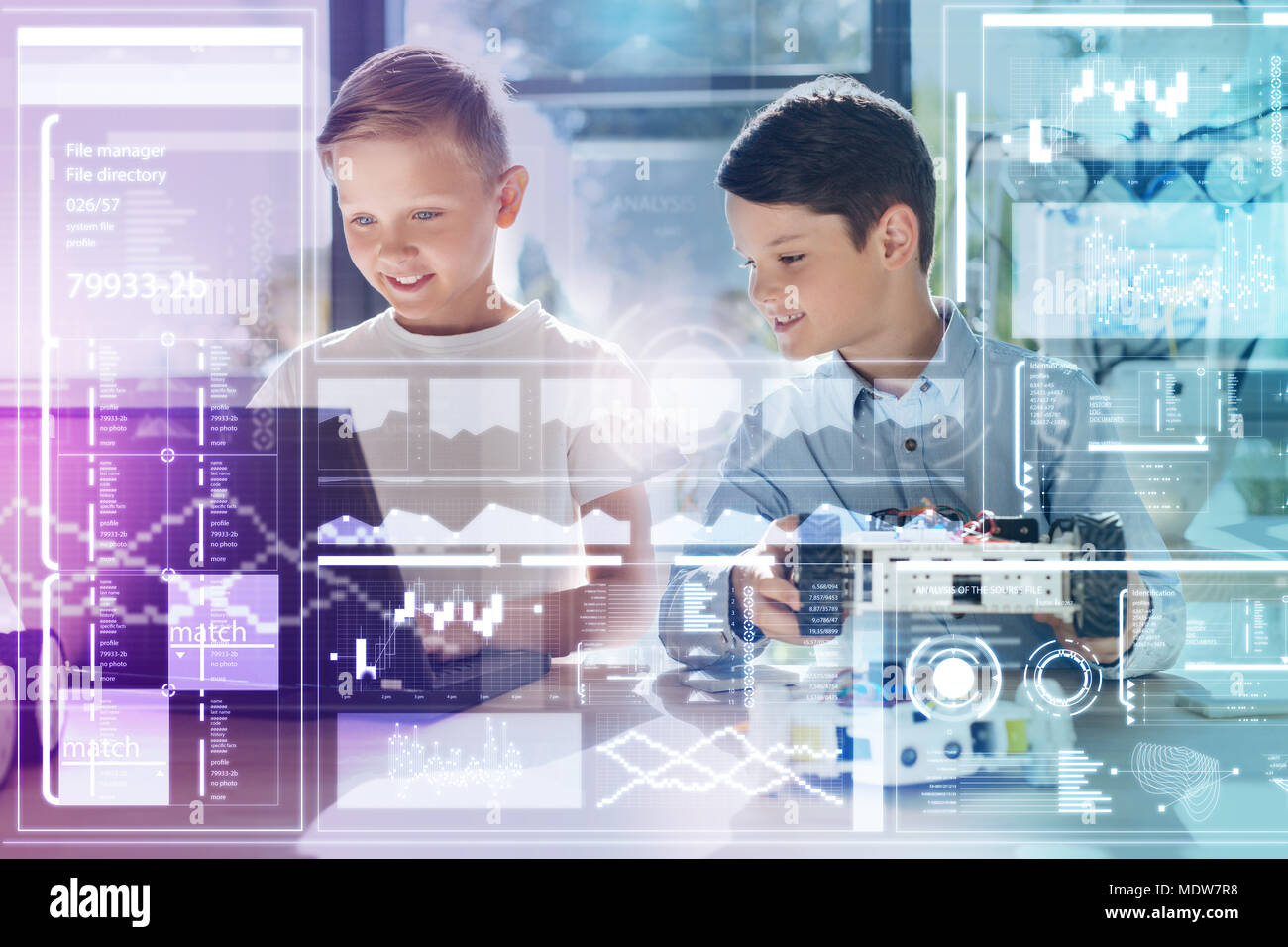 Cheerful boys feeling interested while looking at the screen of a ...