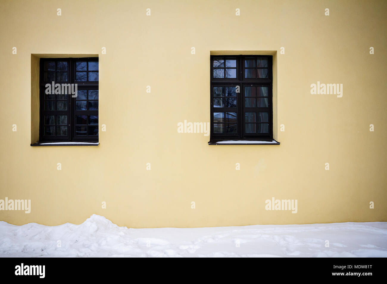 Modern yellow street wall with two windows Stock Photo - Alamy