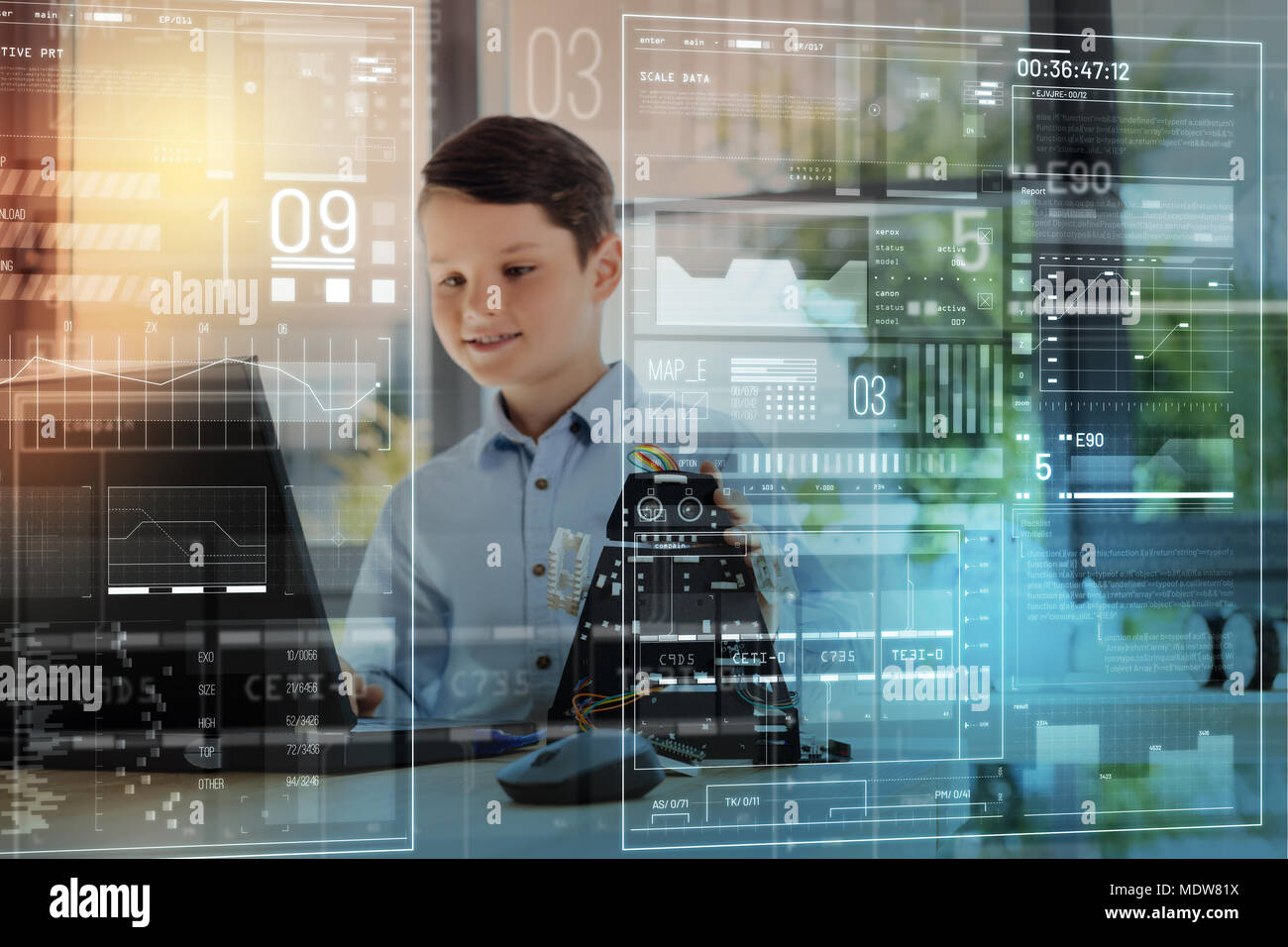 Little inventor looking at the laptop while sitting with his new robot ...