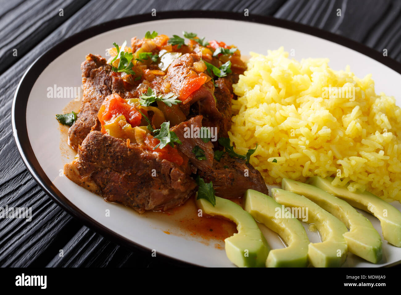 Ecuadorian seco de chivo goat meat with a garnish of yellow rice and ...