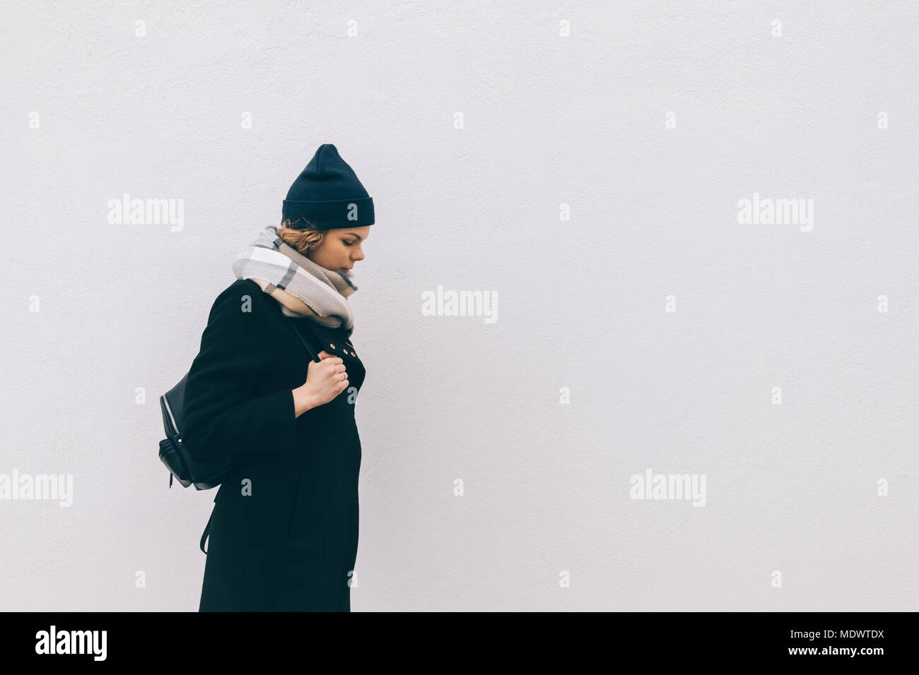 Side view of hipster young woman standing outdoors in cold weather on ...