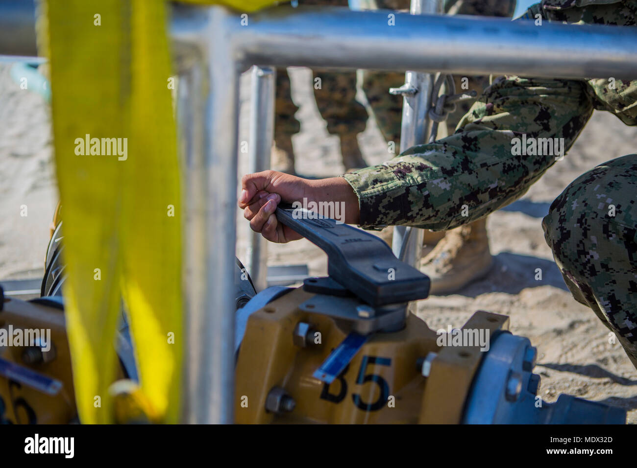 A U.S. Navy Sailor opens a valve of a Beach Unloading Assembly to allow ...