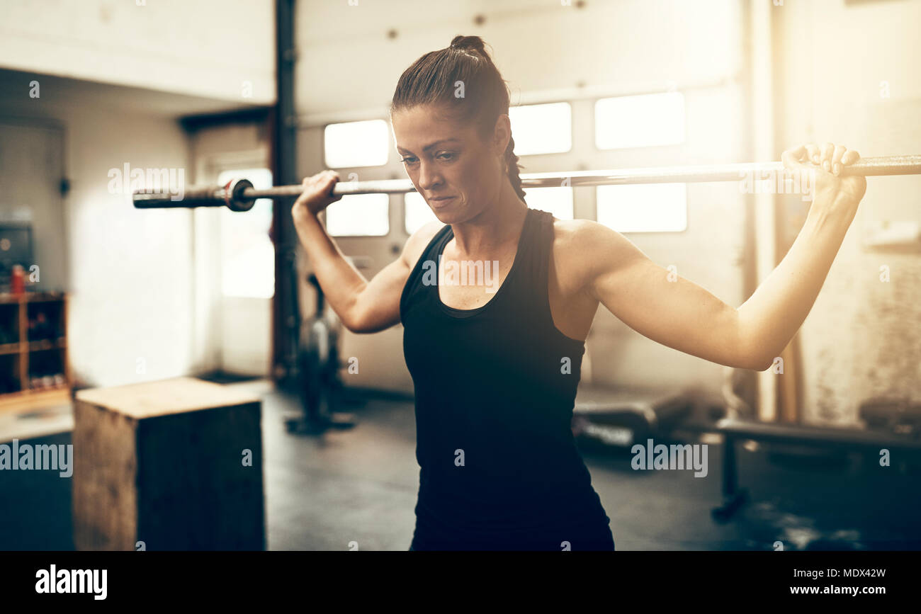 Fit young woman in sportswear standing alone in a gym working out with ...