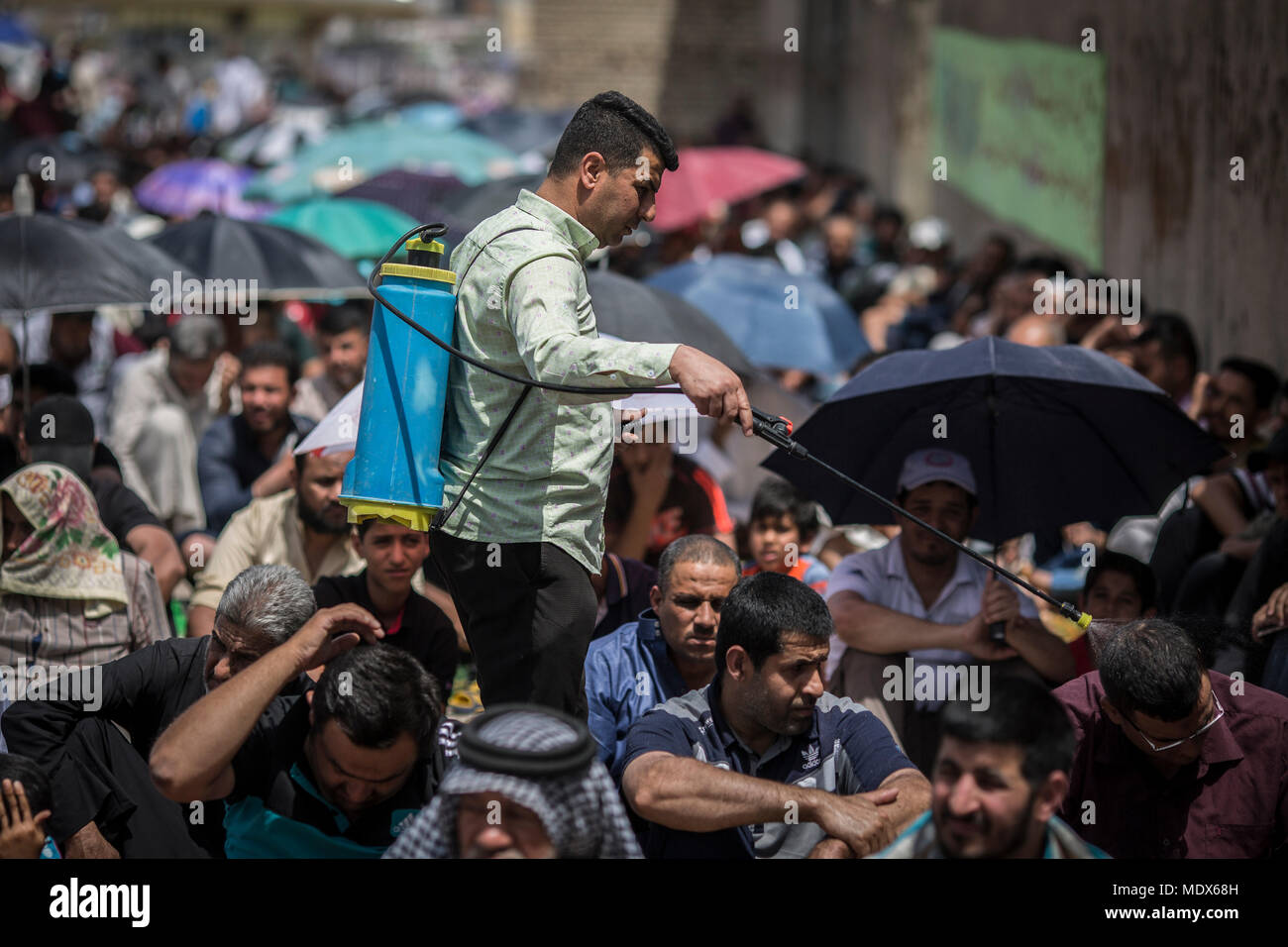 Baghdad, Iraq. 20th Apr, 2018. A man sprays Iraqis attending Friday ...