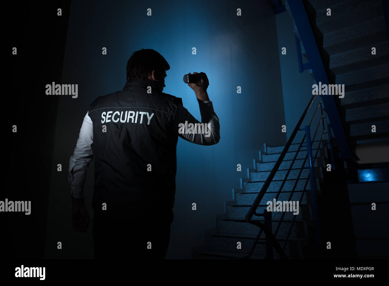 Rear View Of A Security Guard Standing Near Stairway Holding Flashlight ...