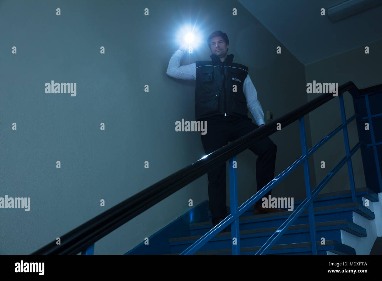 Male Security Guard Standing On Staircase Holding Flashlight Stock ...