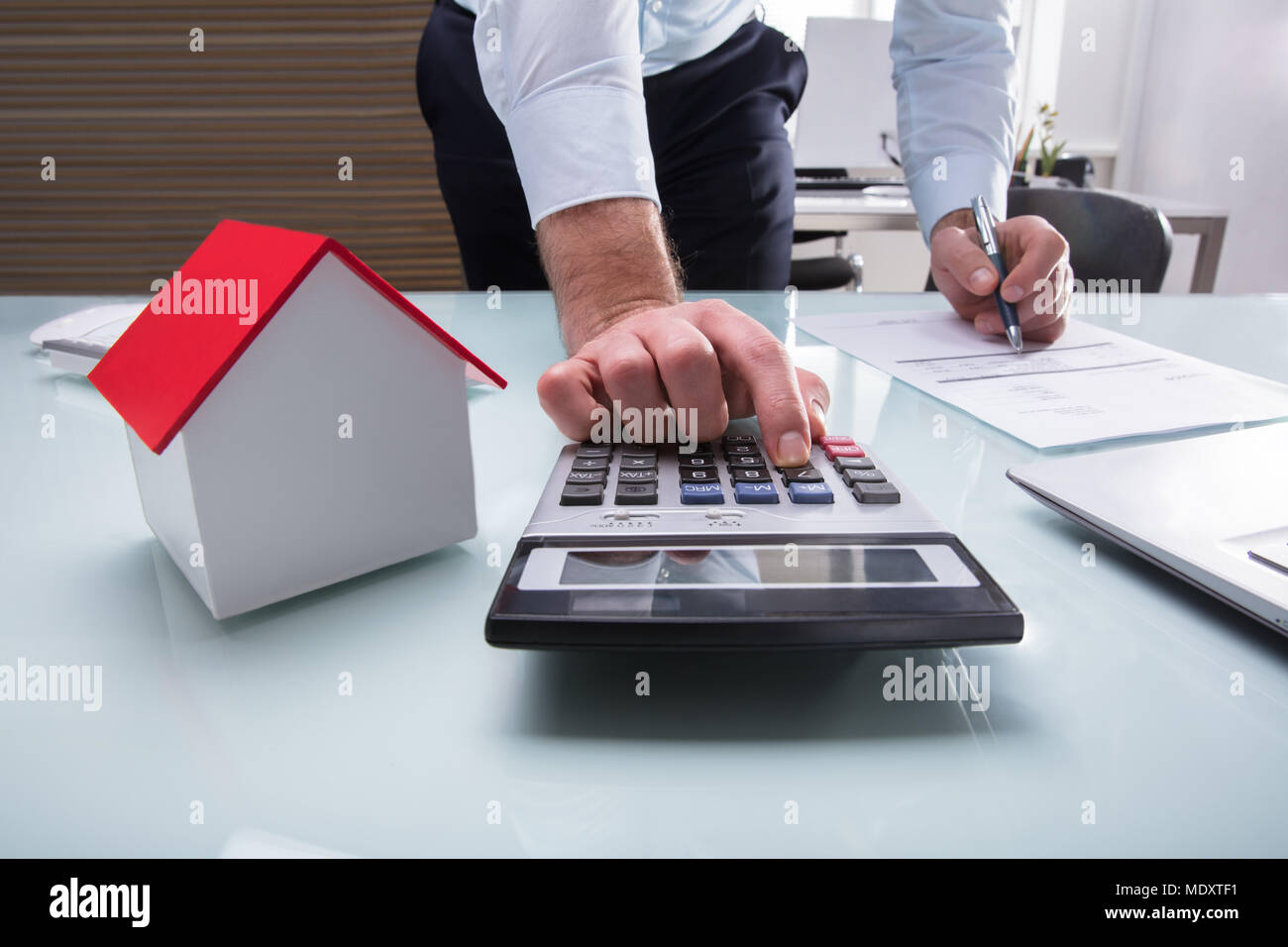 Human Hand Calculating Bill Using Calculator With House Model On Desk ...