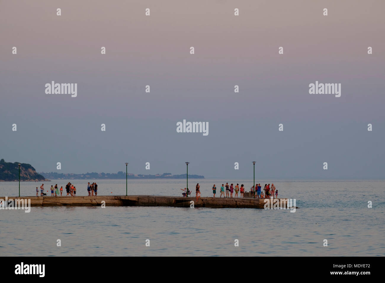 Many people on a pier in warm dusk light Stock Photo - Alamy