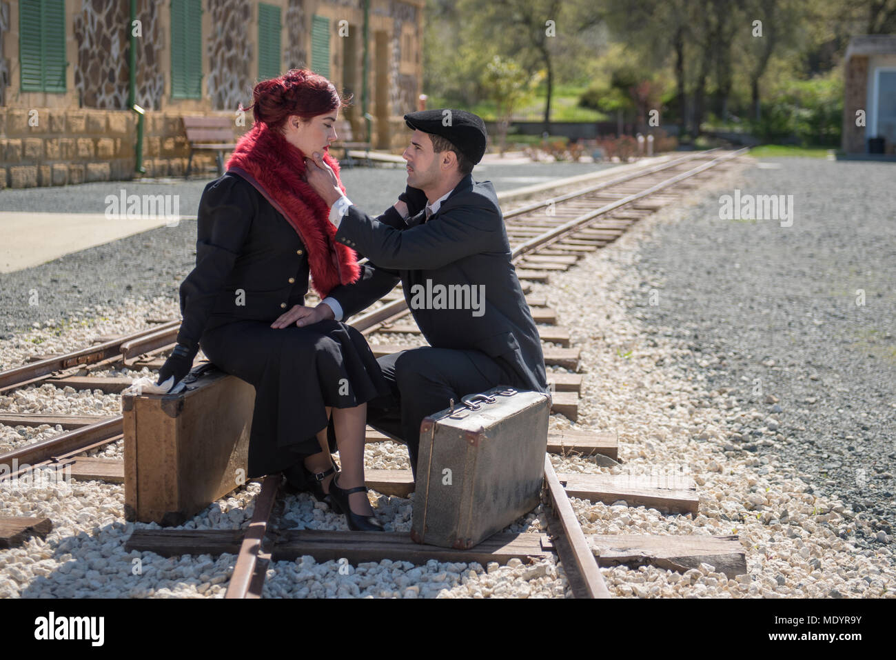 Young couple woman crying and in deep thoughts siting on the trainlines ...