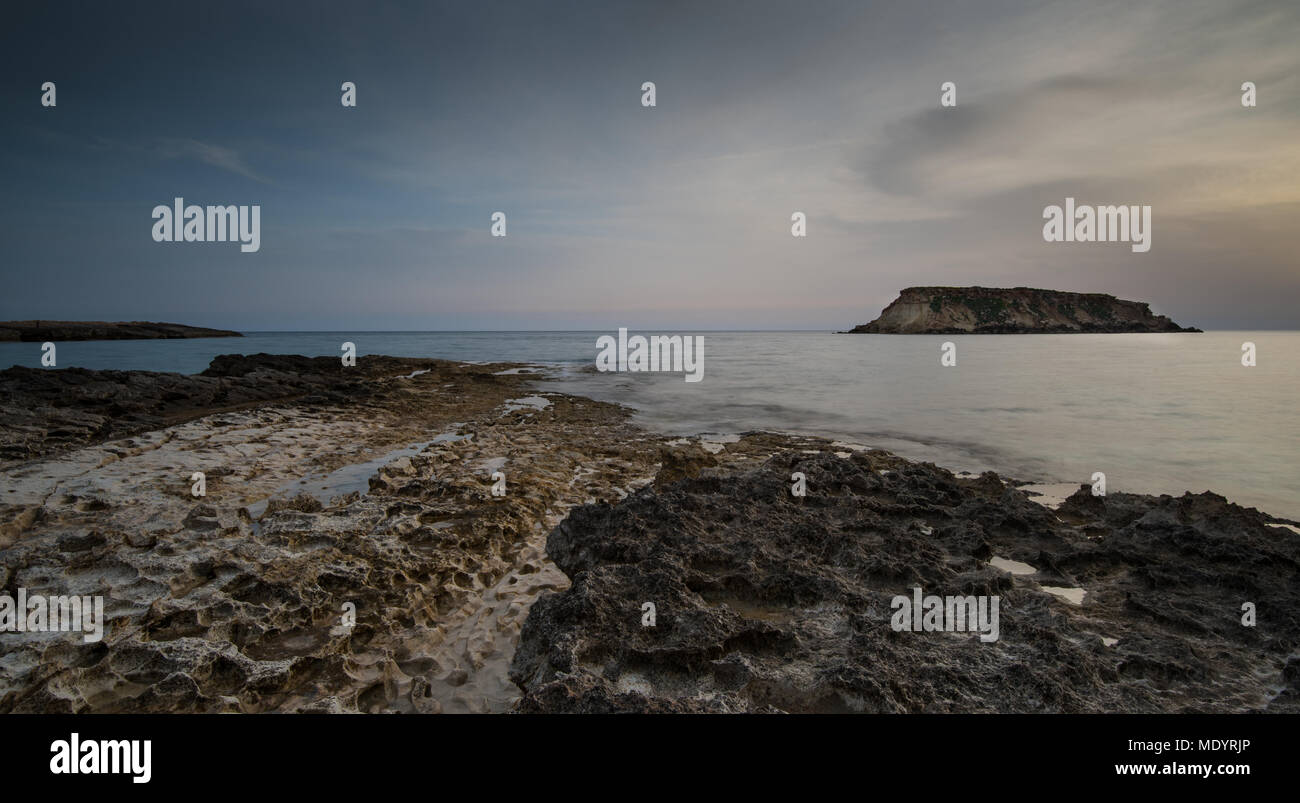 Rocky Seascape at dramatic sunset with the small island of Geronisos at ...
