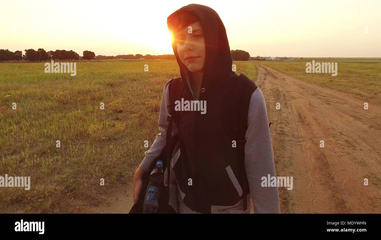 Boy teen traveling. Boy teenage tramp walking along the road in hood ...