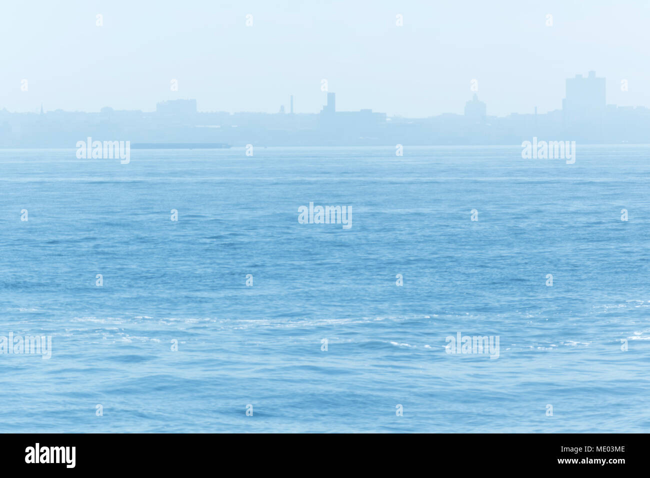 Misty sea on blue sky and city skyline in background Stock Photo - Alamy