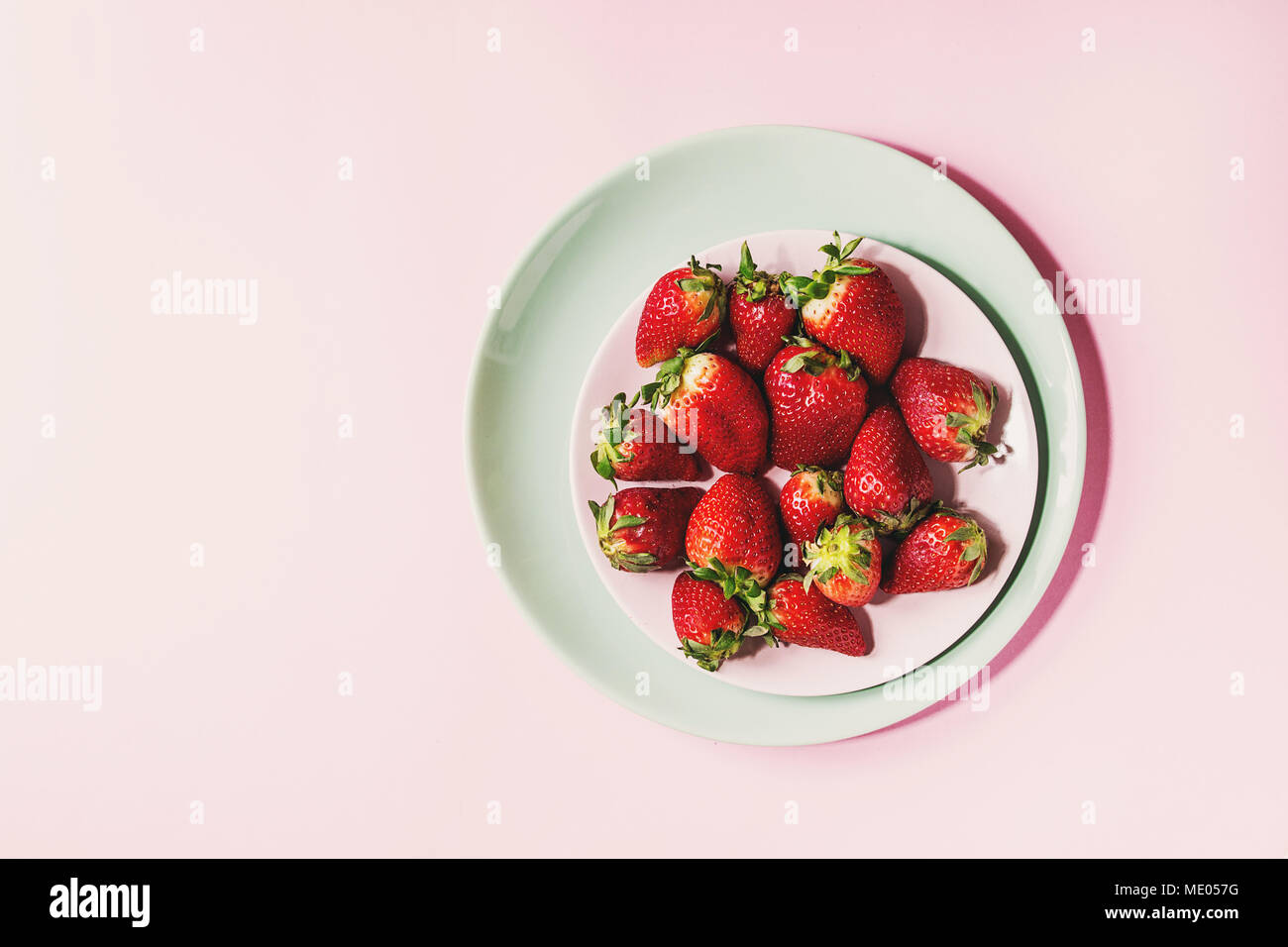 Fresh strawberries on turquoise plate over pink pastel pin-up ...