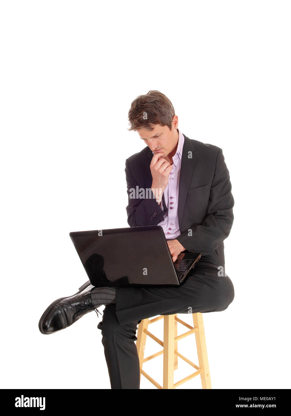 A handsome young business man sitting in a dark suit on a chair with ...