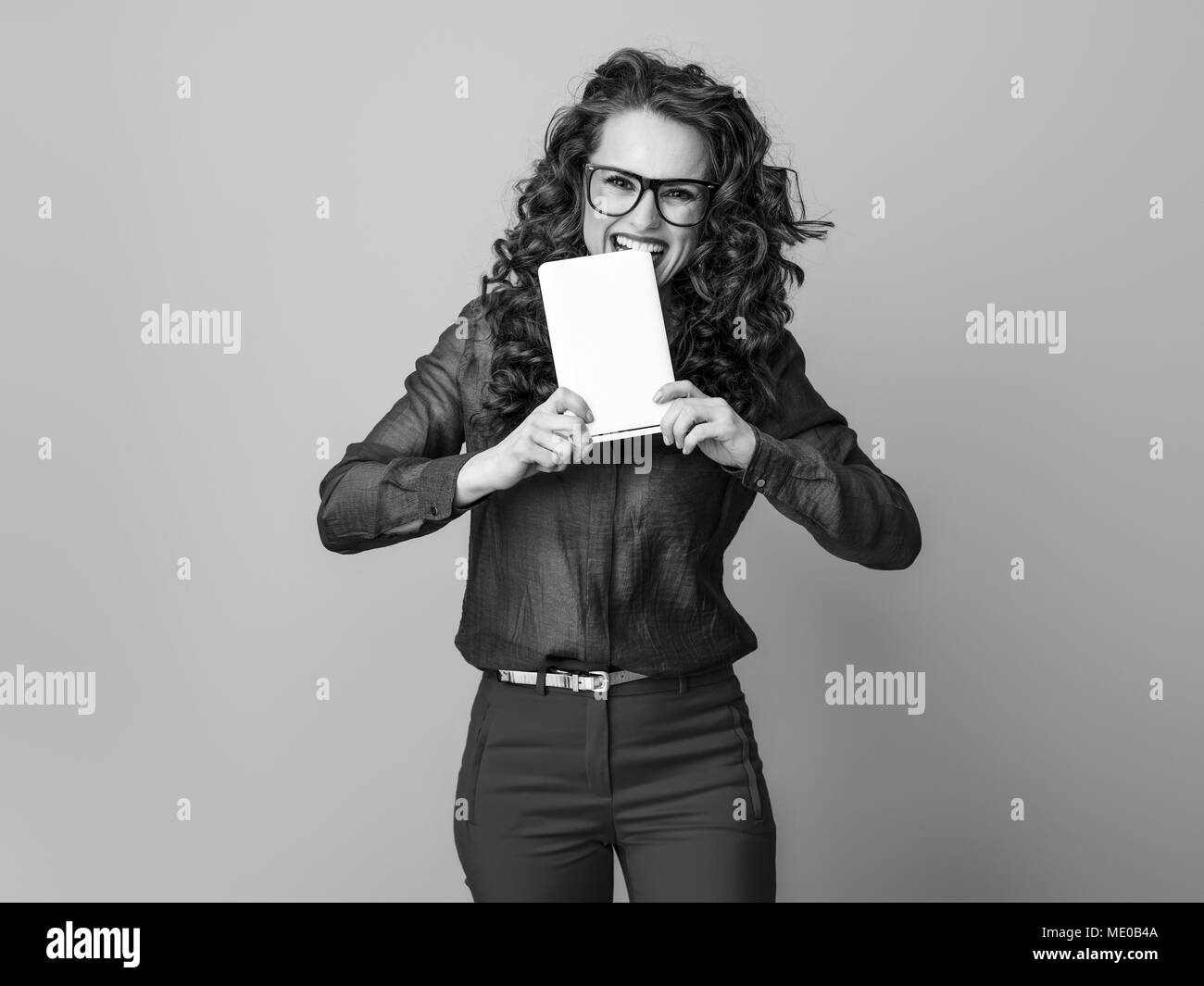 Portrait of smiling trendy woman with long wavy brunette hair biting ...