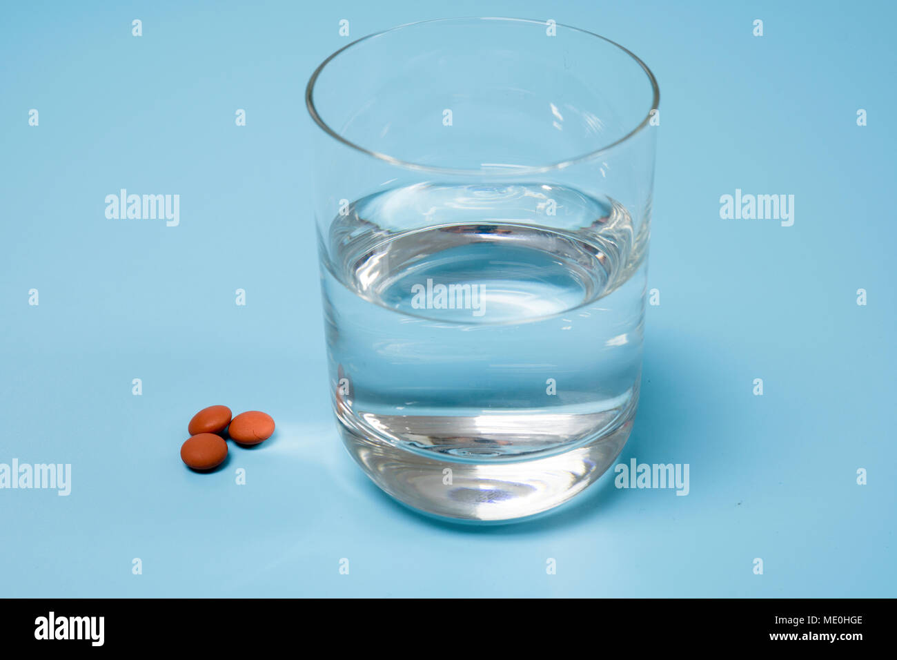 Medication and glass of water on a blue background Stock Photo - Alamy