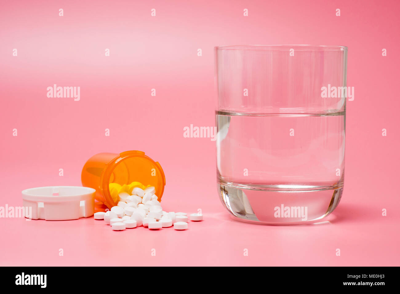 Medication and glass of water on a red background Stock Photo - Alamy