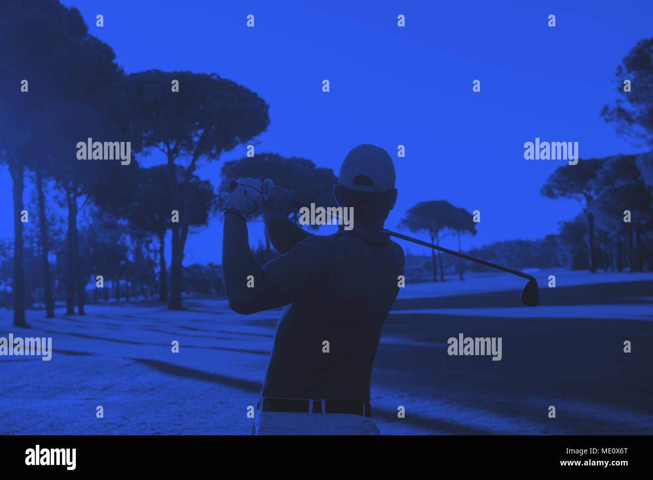 handsome sporty man, golf player hitting shot with club on course at ...