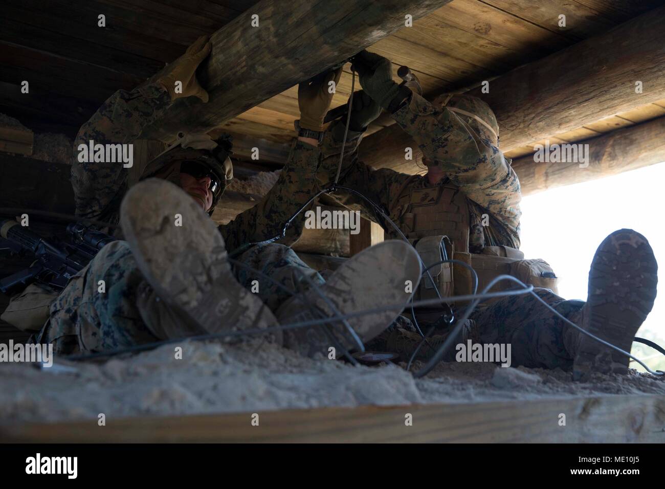 Marines set explosive charges underneath a timber bridge during a ...