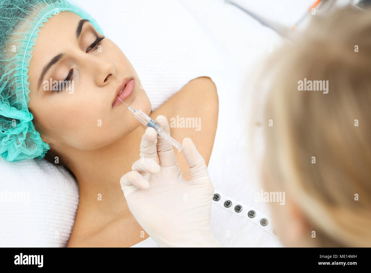 Professional cosmetologist making injection in face, lips. Young woman ...