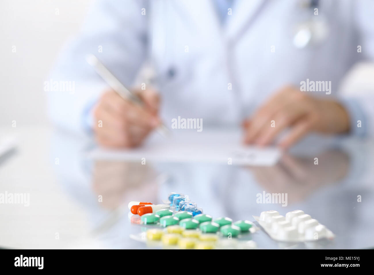 Medicine pills closeup with doctor writing prescription form back in ...