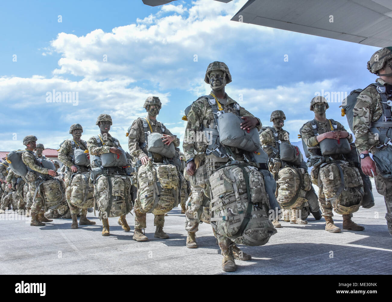 With beautiful blue skies overhead, paratroopers with full combat loads ...