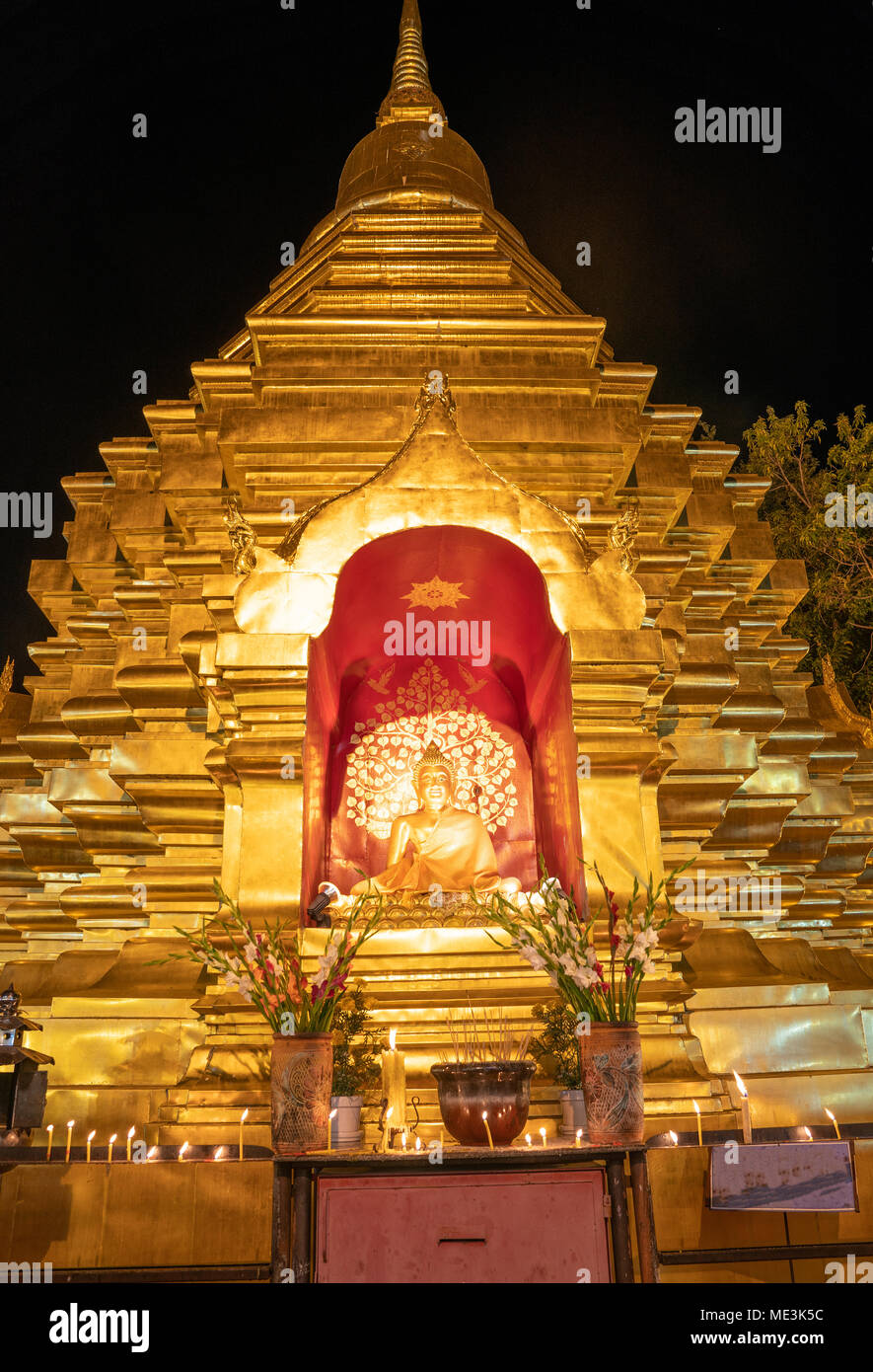 Buddhist shrine finished golden glowing under lights in vertical night ...