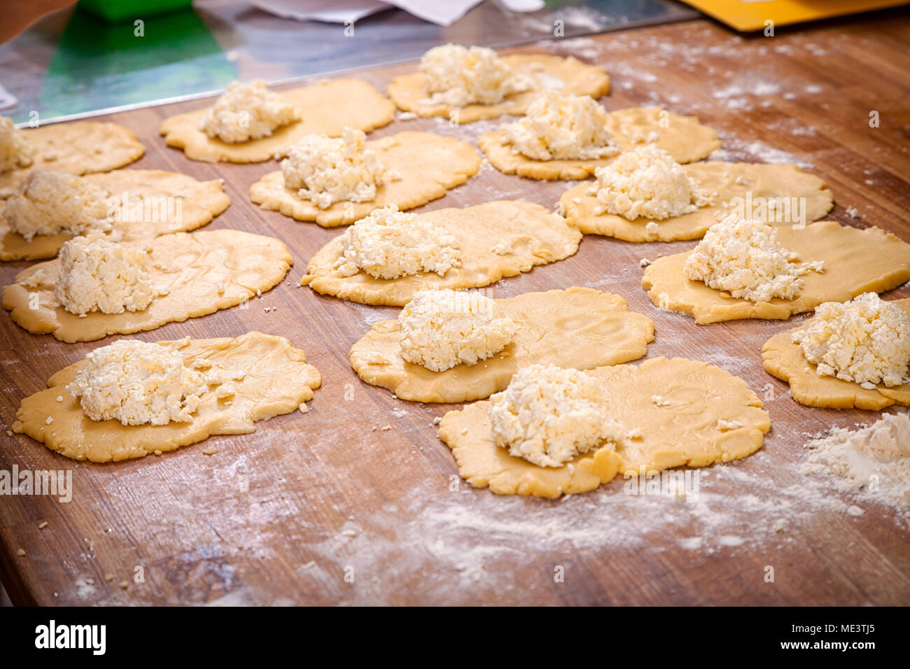 A close-up of the process of cooking buns with cheese on a wooden table ...