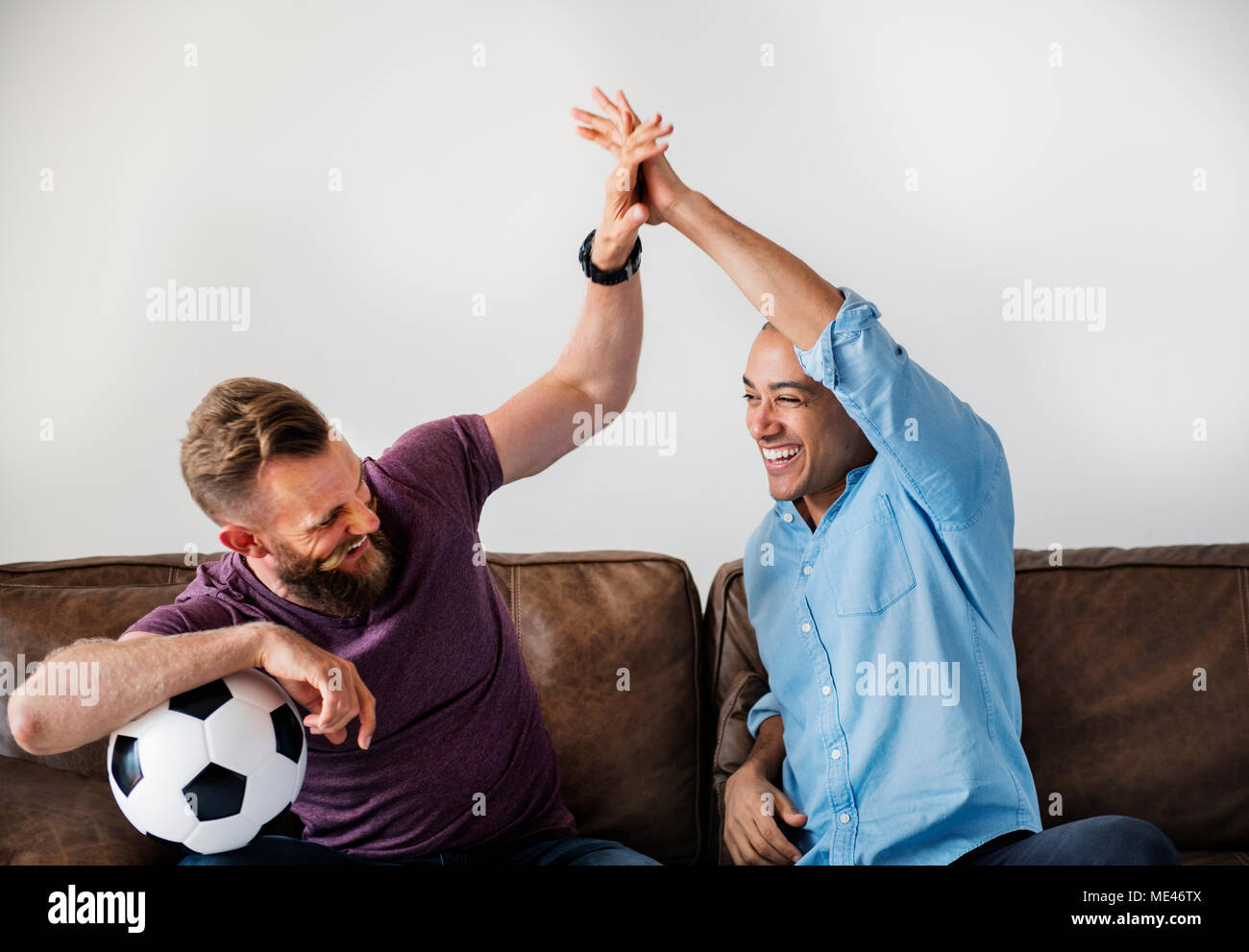 Man sitting together on a couch watching sport Stock Photo - Alamy