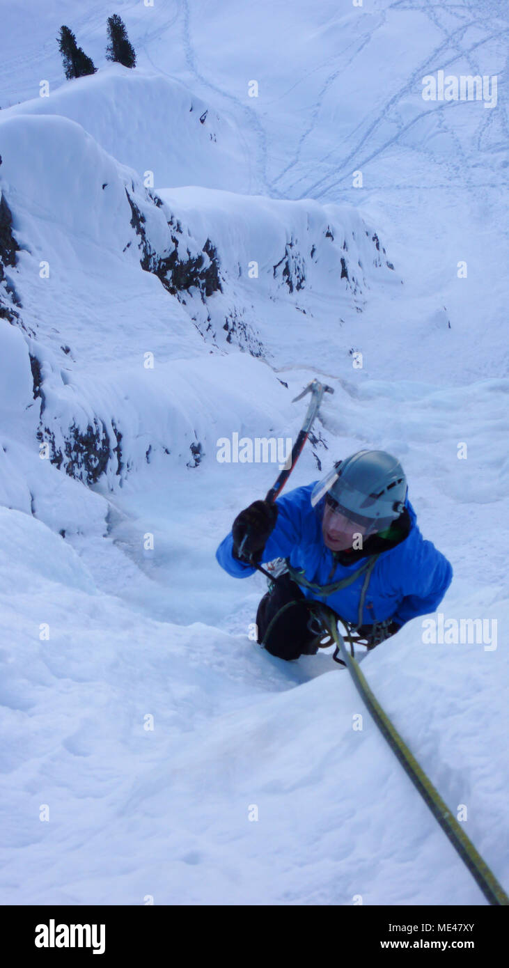 male ice climber on a steep icefall in the Swiss Alps near Davos Stock ...