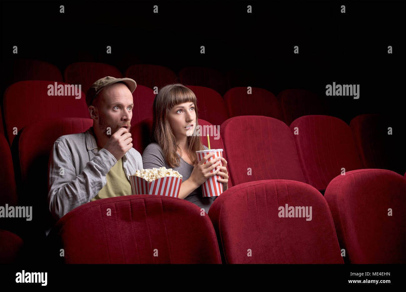 Young cute couple sitting alone at red movie theatre and having fun ...