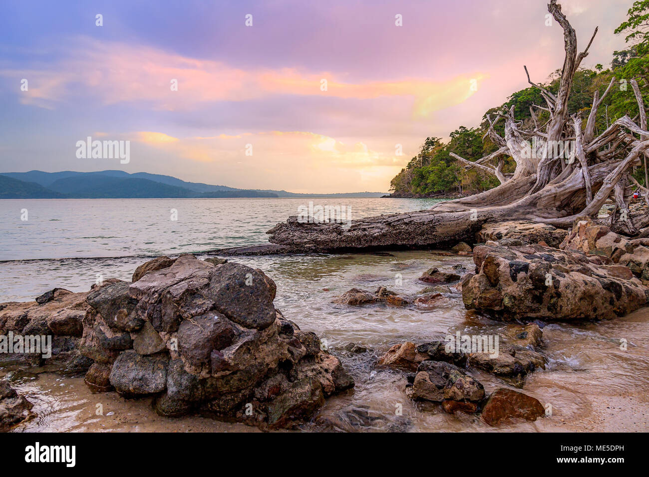 Beach sunset with rocks boulders and fallen tree trunk at Chidiya Tapu ...