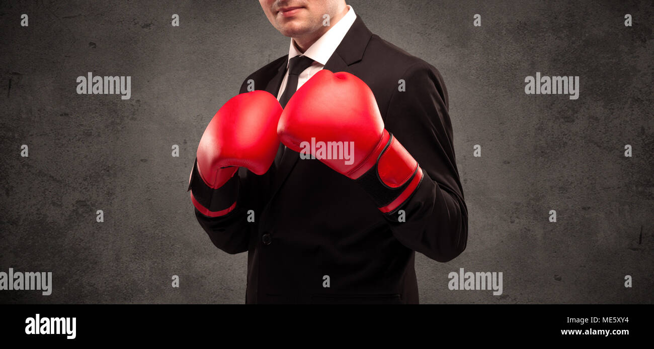 A well dressed sales person standing with red boxing gloves on his hand ...