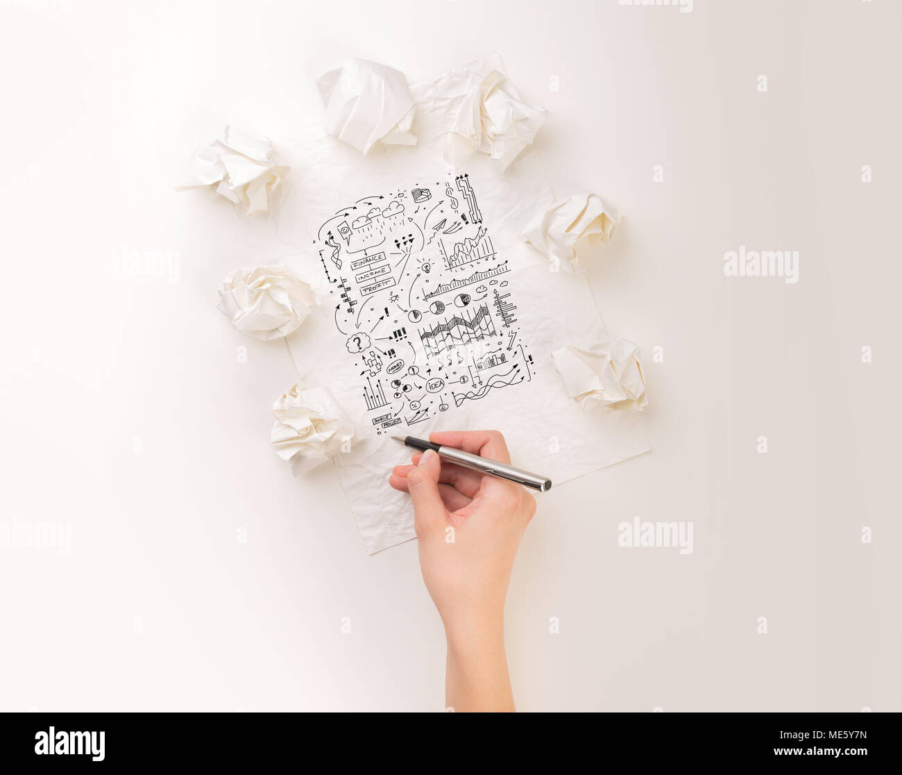 Female hand next to a few crumpled paper balls drawing charts and ...